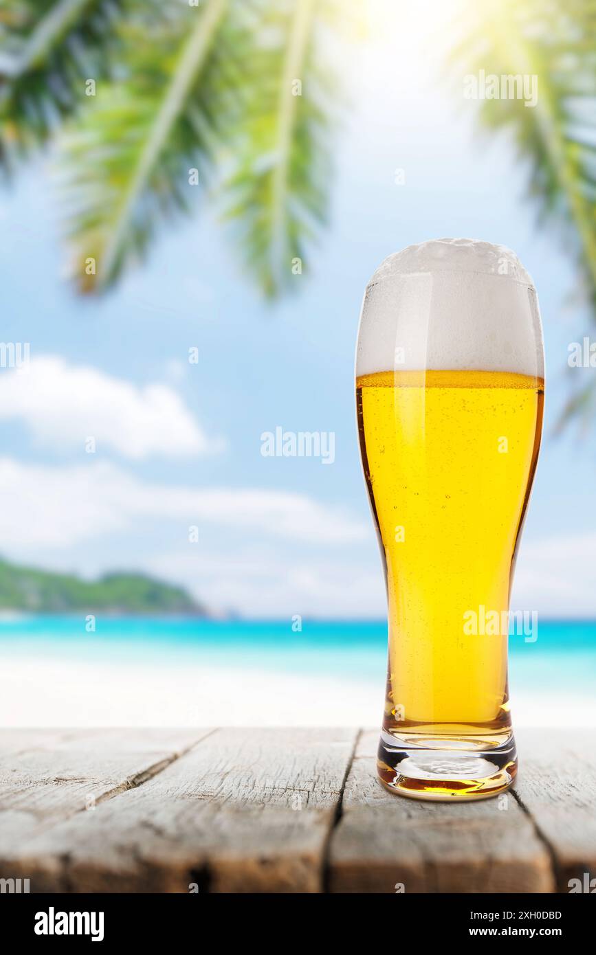 Glass of beer on a table with a stunning sea and beach background ...