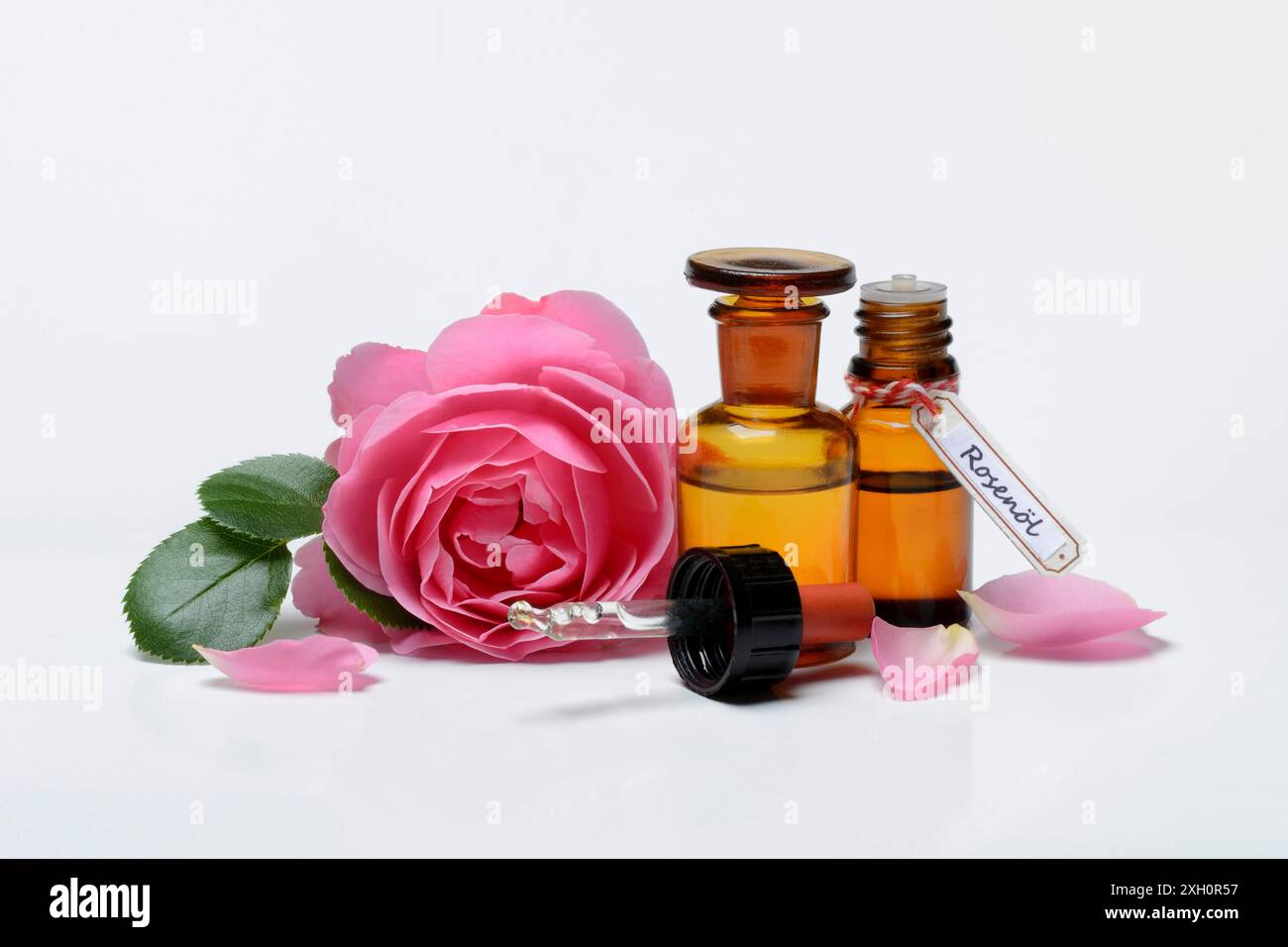 Rose oil, rose blossom and rose oil in vials Stock Photo - Alamy