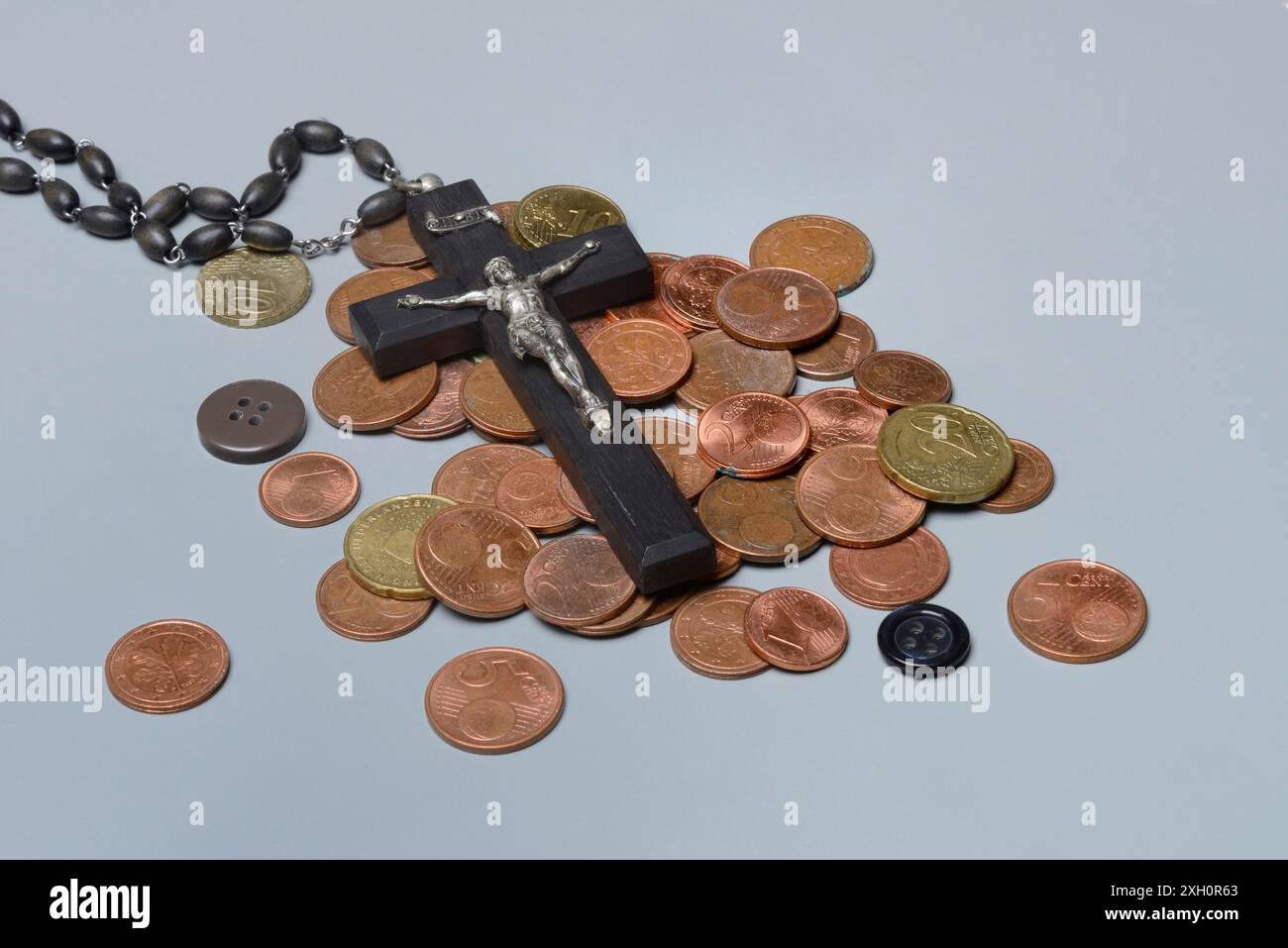 Crucifix with coins and buttons, church and money Stock Photo - Alamy