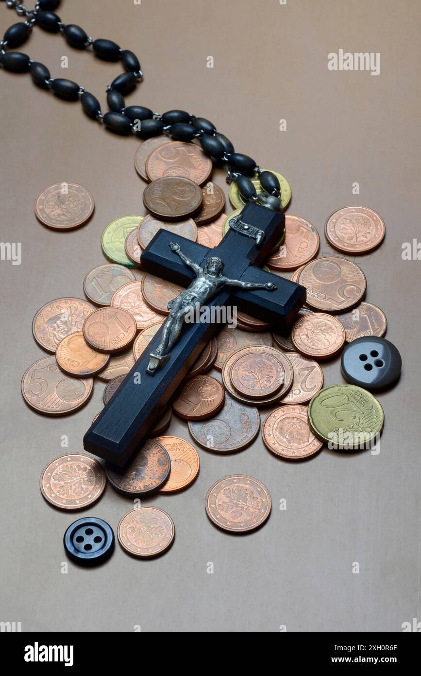 Crucifix with coins and buttons, church and money Stock Photo - Alamy