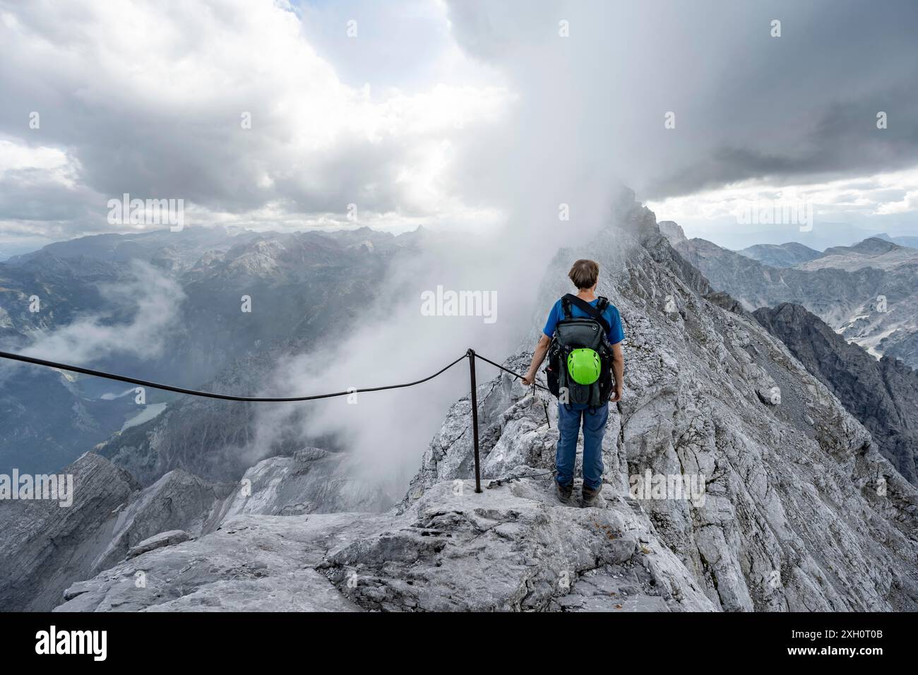 Mountaineer on a narrow rocky ridge on a steel cable, Watzmann crossing ...