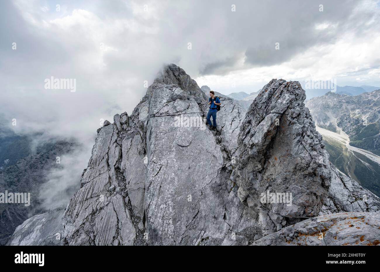 Mountaineer on a narrow rocky ridge on a steel cable, Watzmann crossing ...