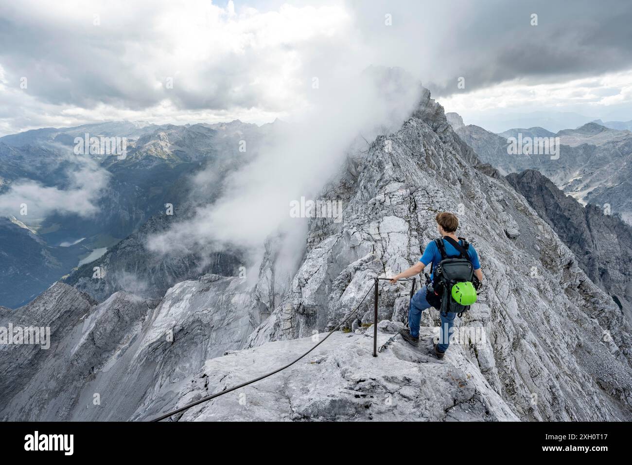 Mountaineer on a narrow rocky ridge on a steel cable, Watzmann crossing ...