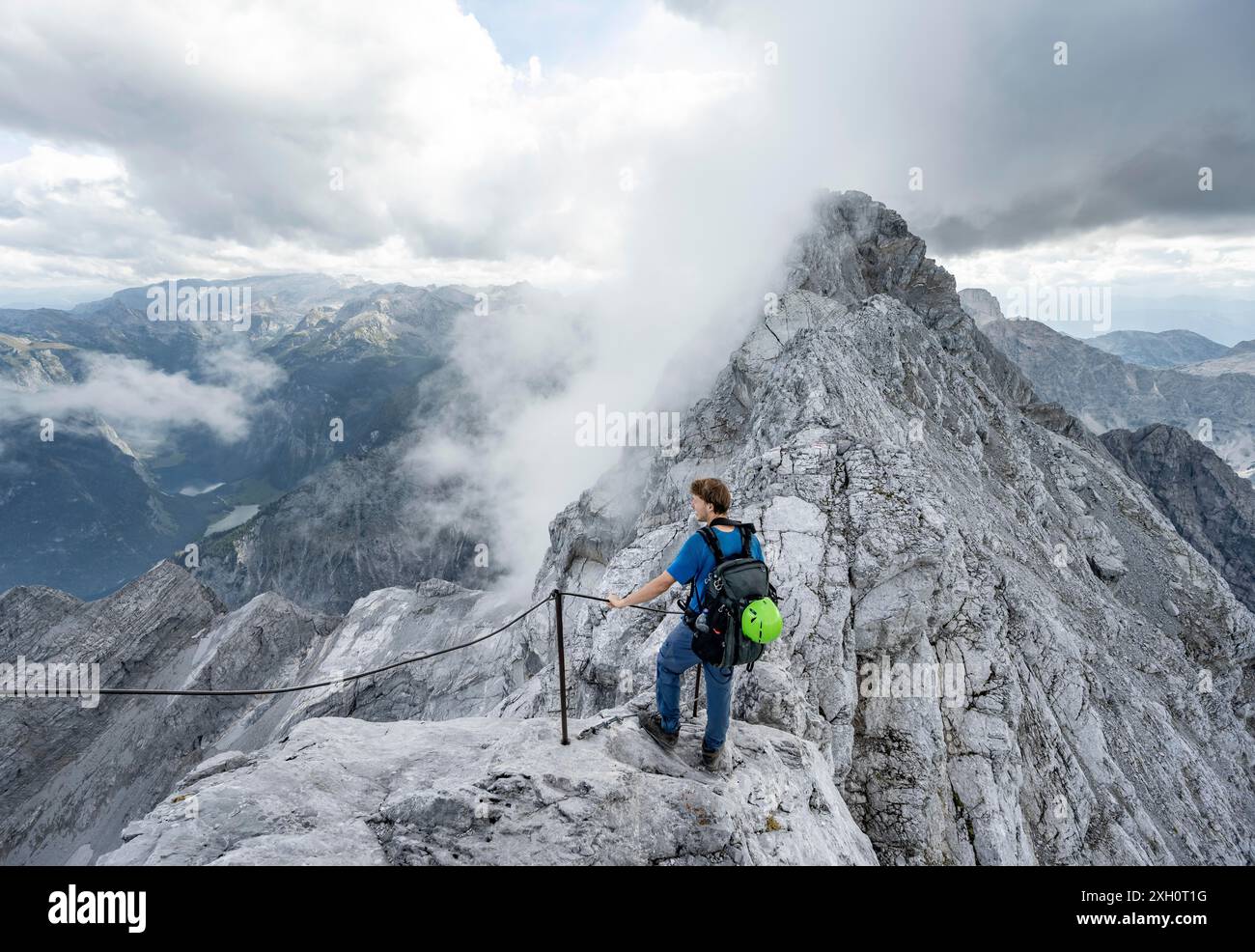 Mountaineer on a narrow rocky ridge on a steel cable, Watzmann crossing ...