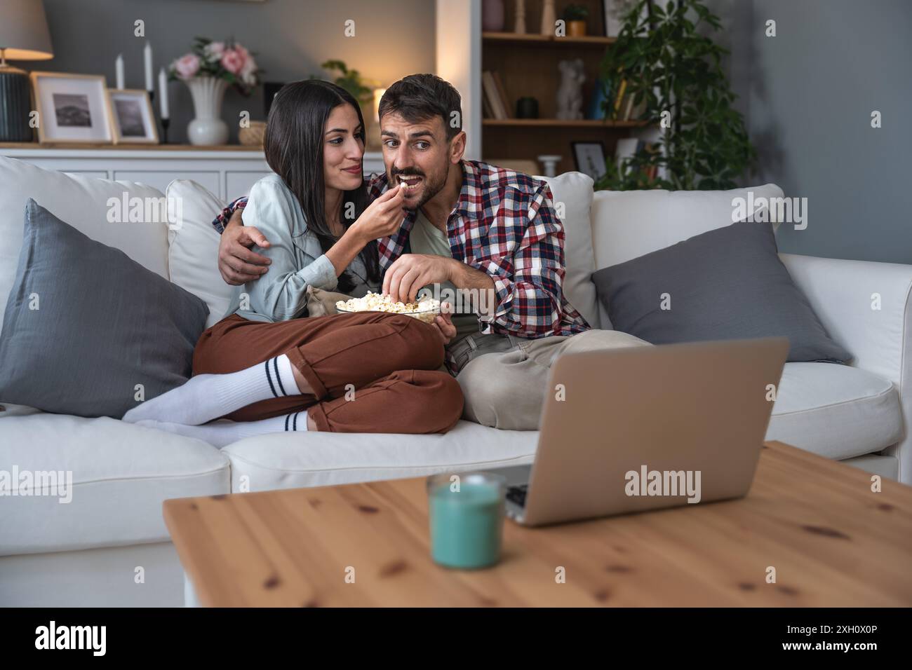 Couple shocked watching horror movie on laptop computer sitting at sofa ...