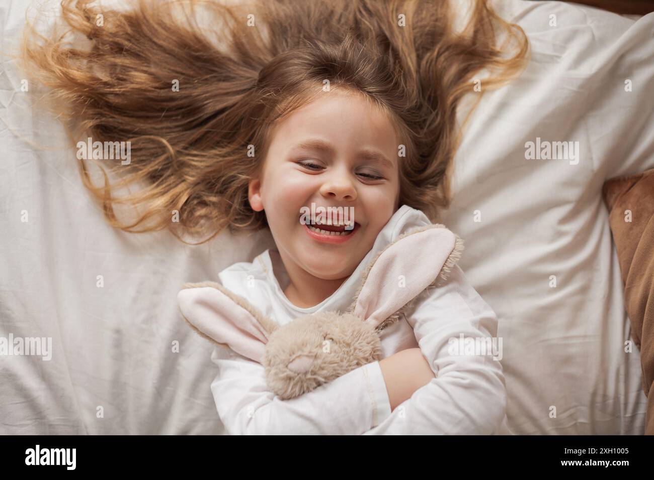 Portrait of happy child. Little beautiful curly girl hugging her plush ...