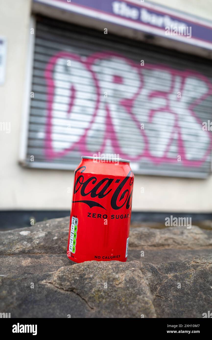 Zero sugar coca cola can left on a wall with graffiti in the background ...