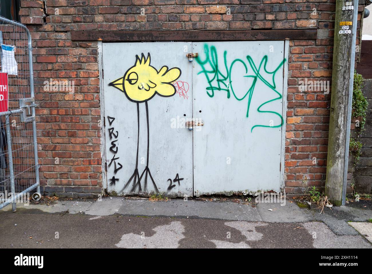 Yellow bird with long legs spray painted on white garage doors Stock ...