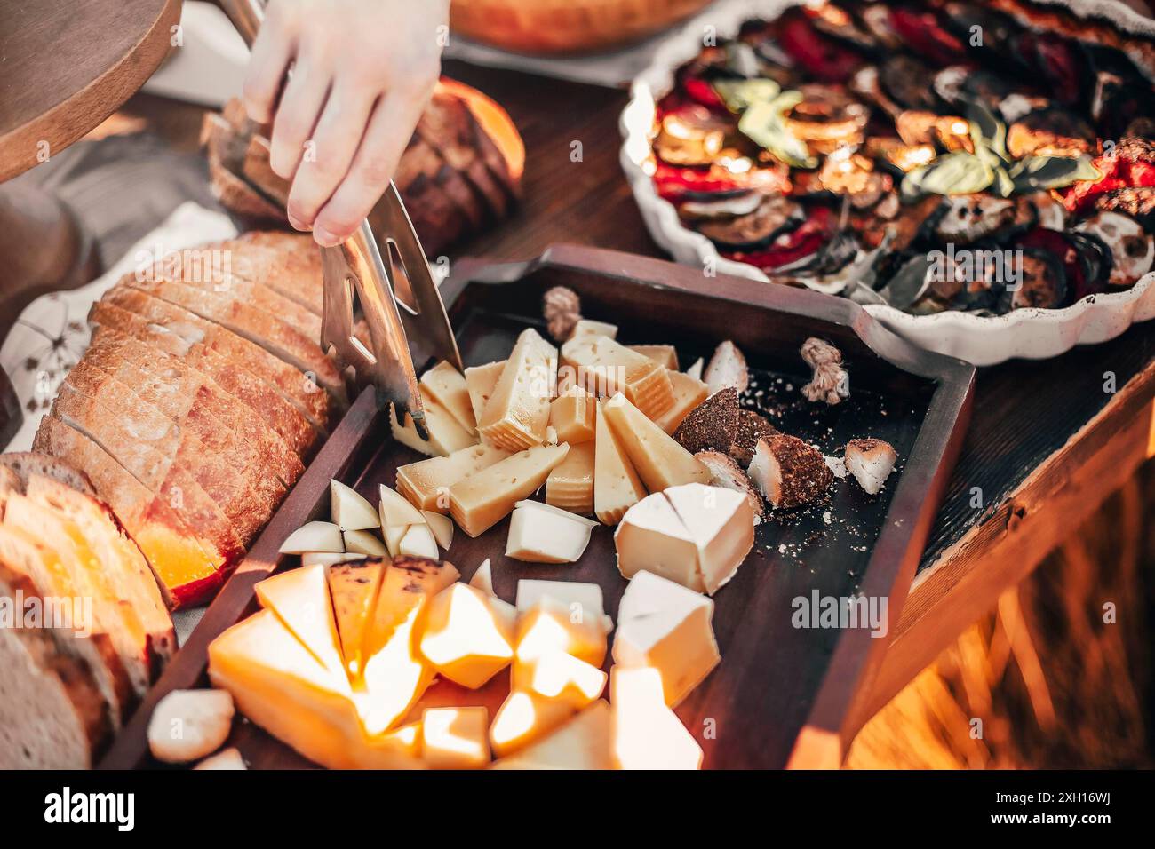 High angle of crop anonymous person with tongs taking piece of cheese ...