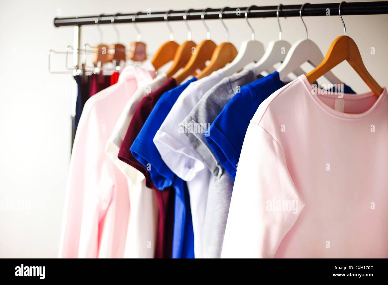 Rack with various feminine shirts placed in minimalist style room with ...