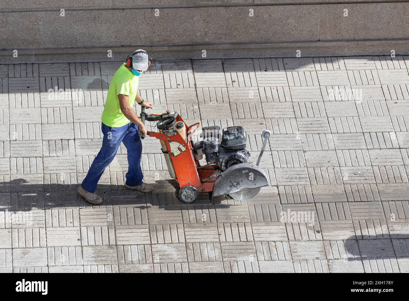 Construction worker cutting paving stone floor with diamond saw blade ...
