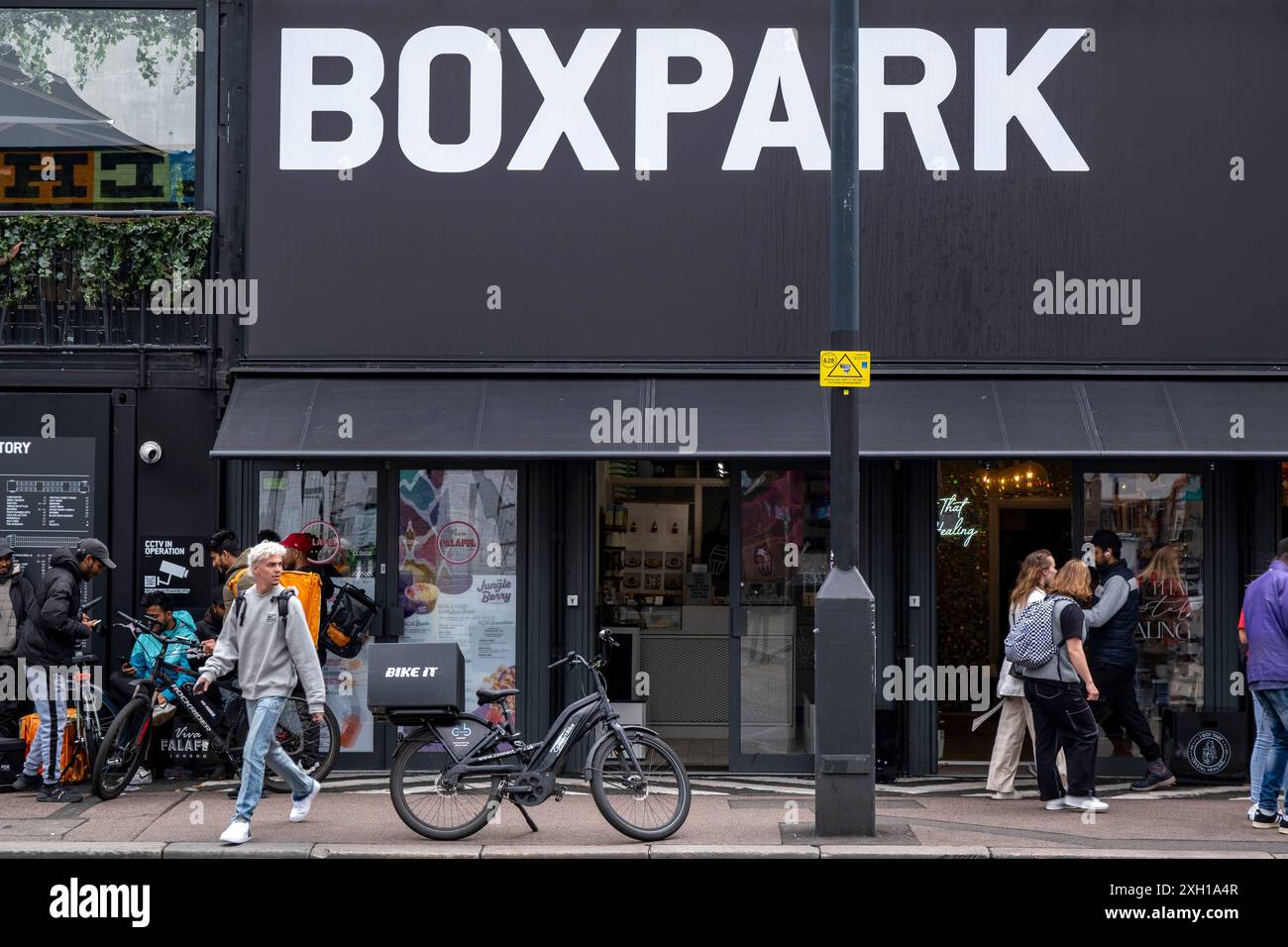 People pass boutique shops at Boxpark in Shoreditch on 3rd July 2024 in ...