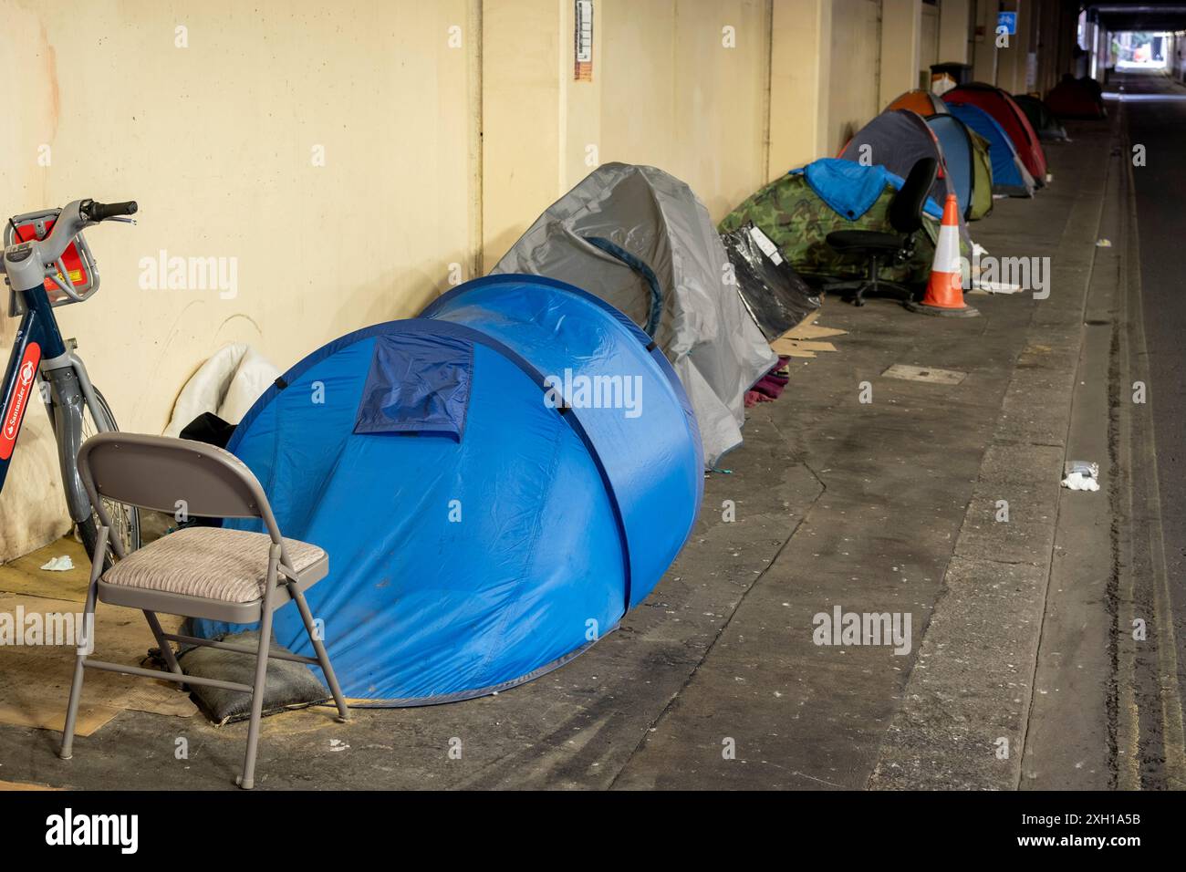 Homeless persons tents pitched in line on the pavement in an underpass ...