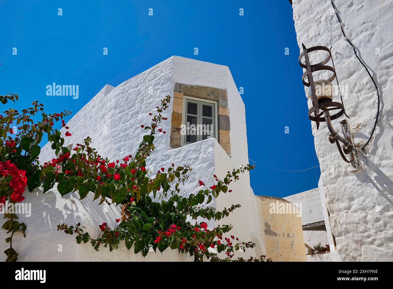 White building with flower tendrils and windows under a bright blue sky ...