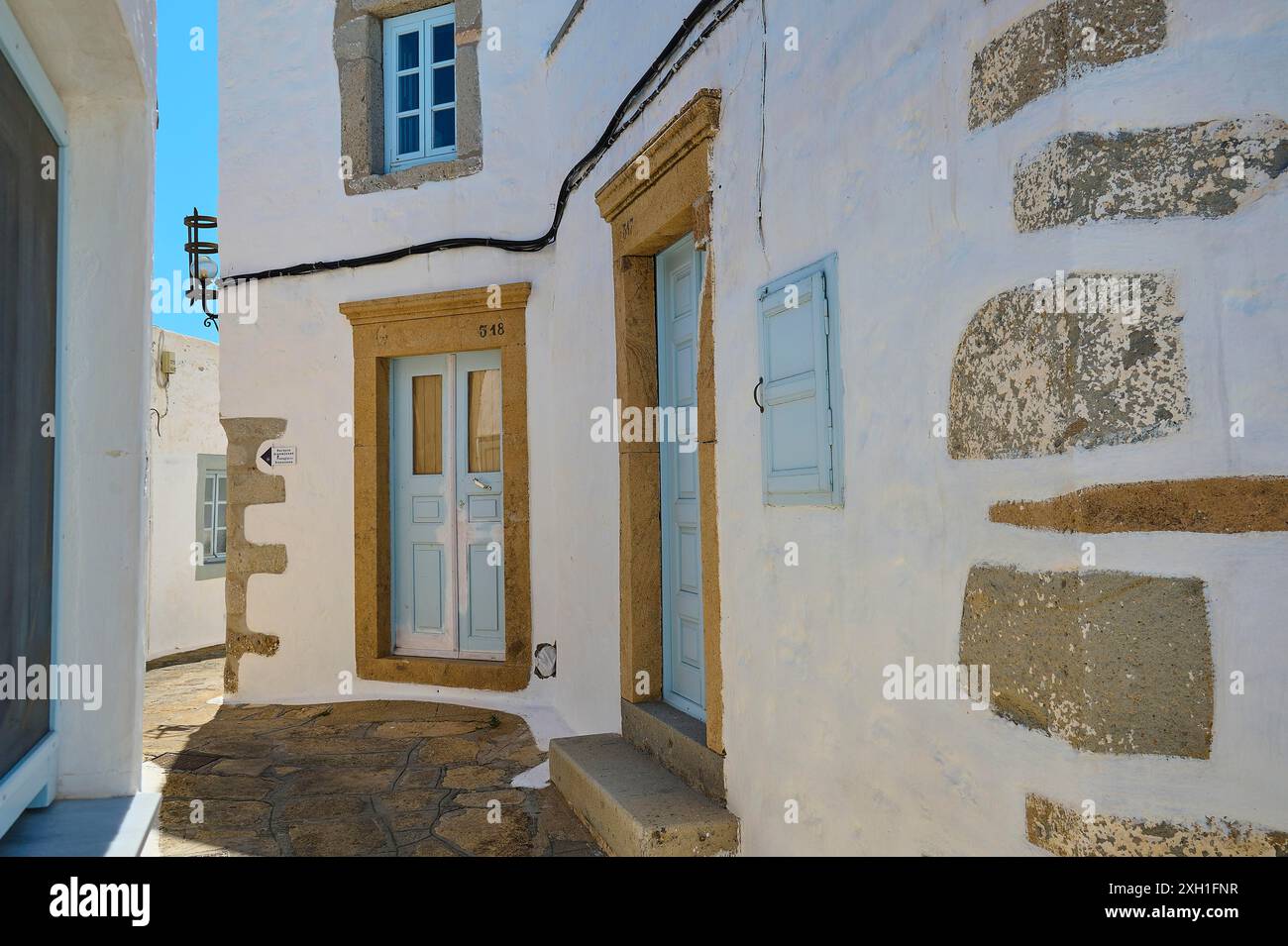 White buildings with blue shutters and stony path, typical Greek ...