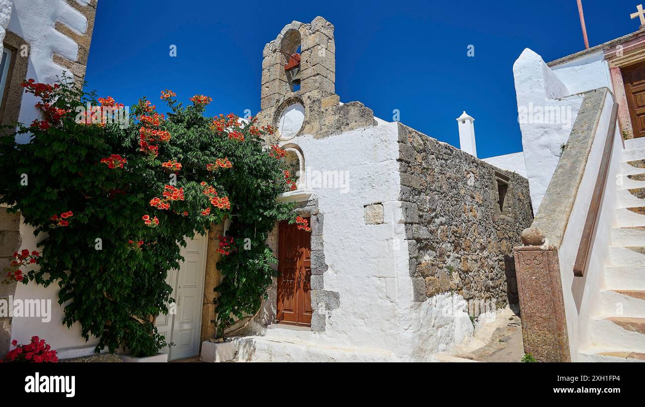White building with bell tower, flower tendrils and staircase under a ...