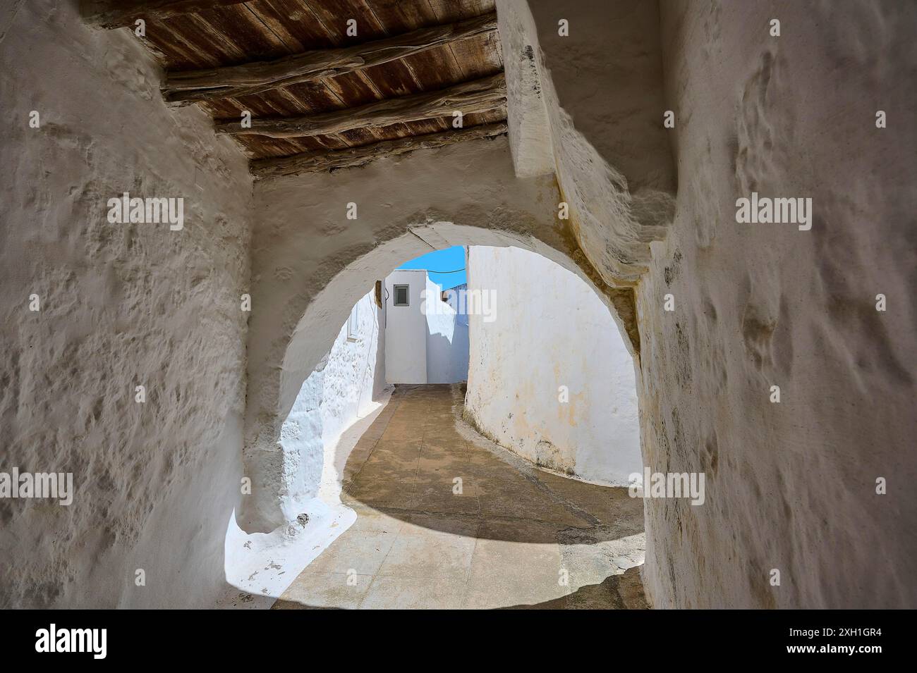 Arched passageway with wooden ceiling and white walls in a historic ...