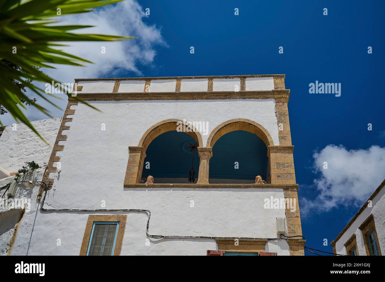 White building with arches and columns under a bright blue sky ...