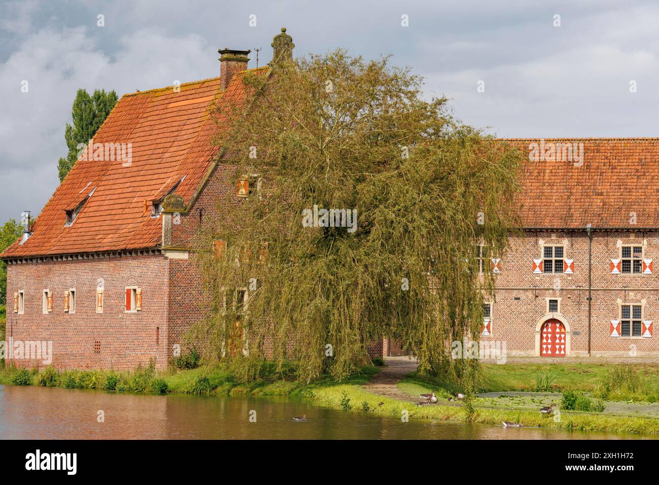 Brick castle with hanging branches of a tree and a surrounding moat ...