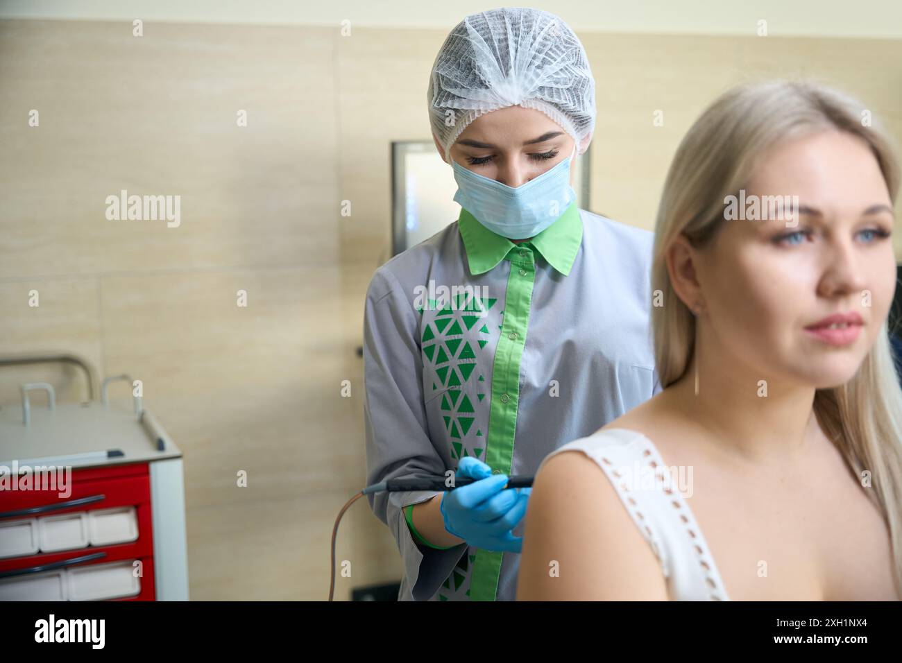 Dermatologic surgeon doing electrocauterization for skin lesion removal ...