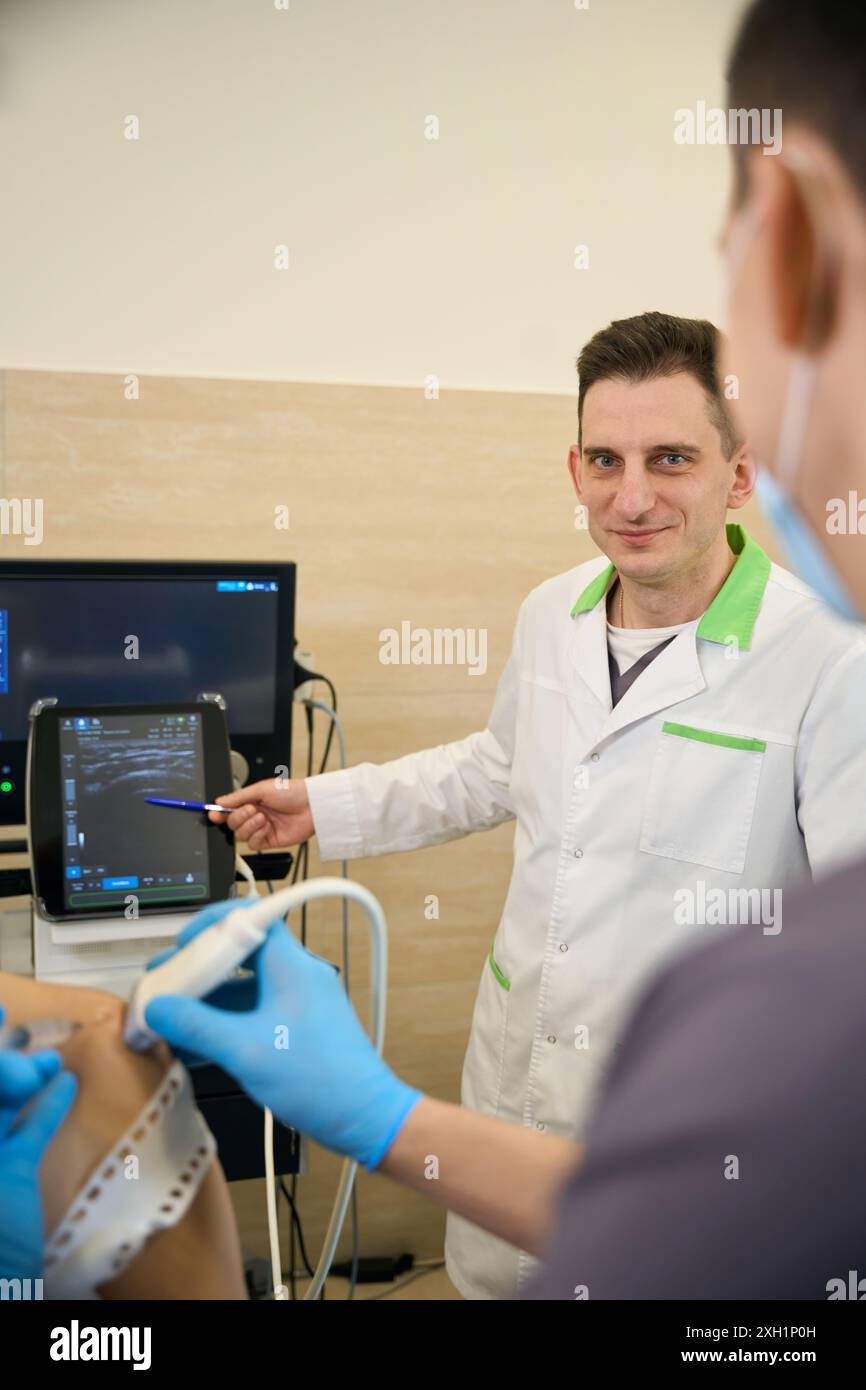 Team of medical professionals carrying out ultrasound-guided shoulder ...