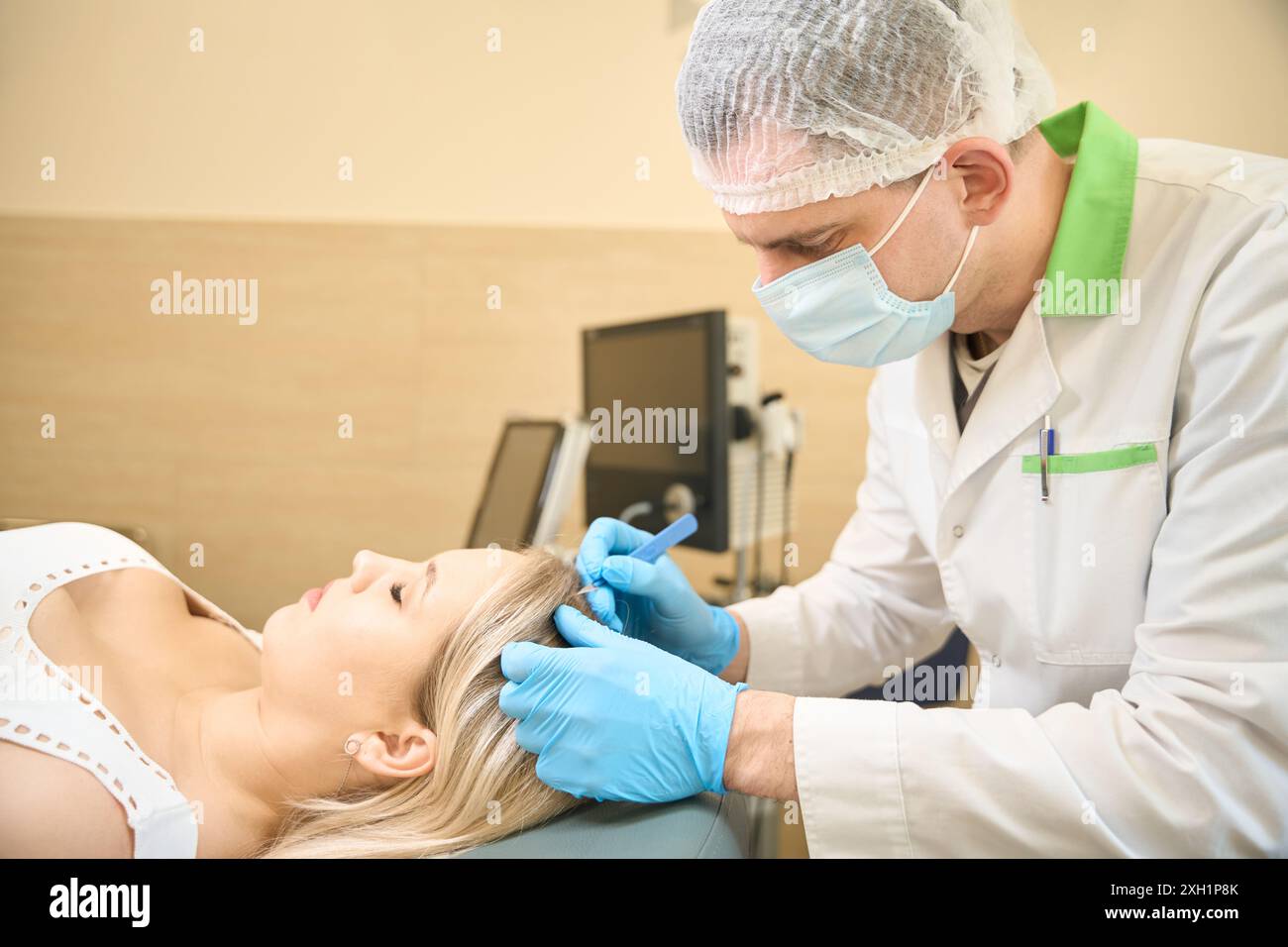 Dermatologic surgeon removing atheroma on female patient scalp using ...