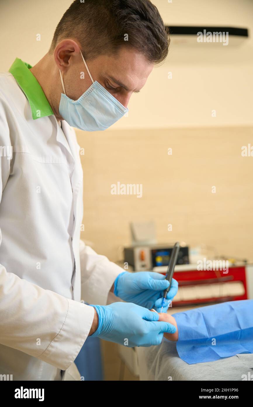 Podiatric surgeon performing skin lesion removal on patient foot Stock ...
