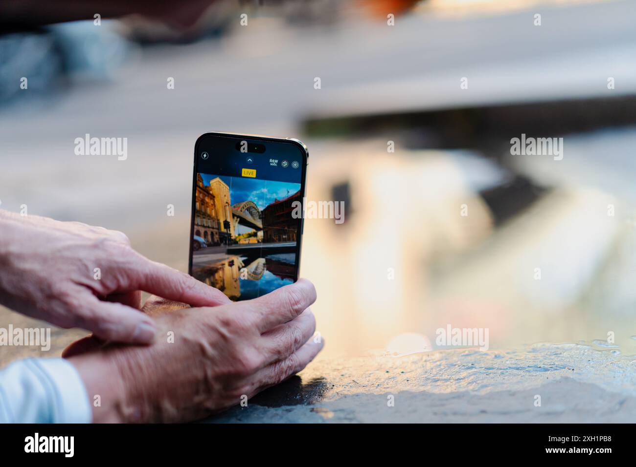 Hands holding a mobile phone photographing the Tyne Bridge, Newcastle ...