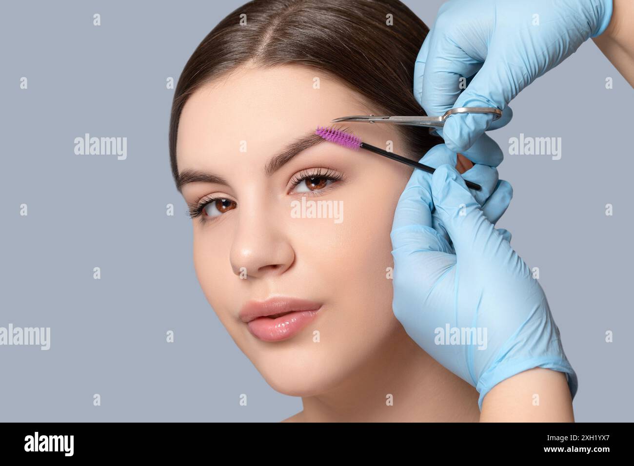 Makeup artist comb and trim the eyebrows with scissorss to a woman ...