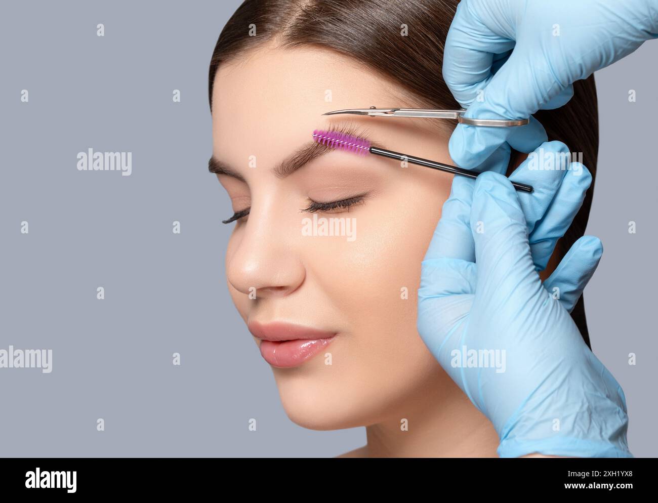 Makeup artist comb and trim the eyebrows with scissorss to a woman ...