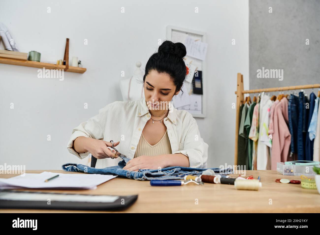 A young woman upcycles clothes, sewing and creating on a piece of cloth ...
