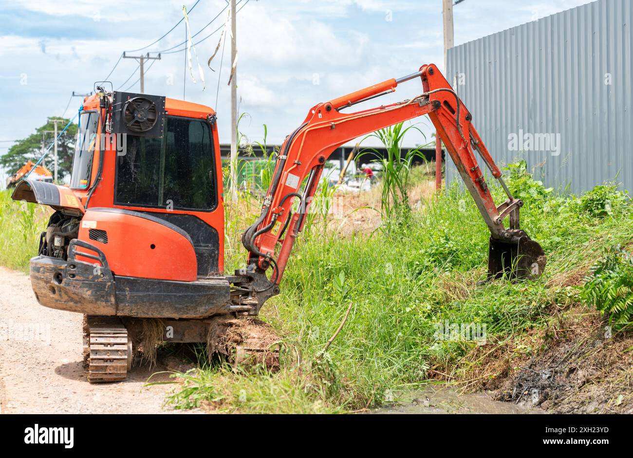 Mini excavator dig drainage canal anc clear grass on a construction ...