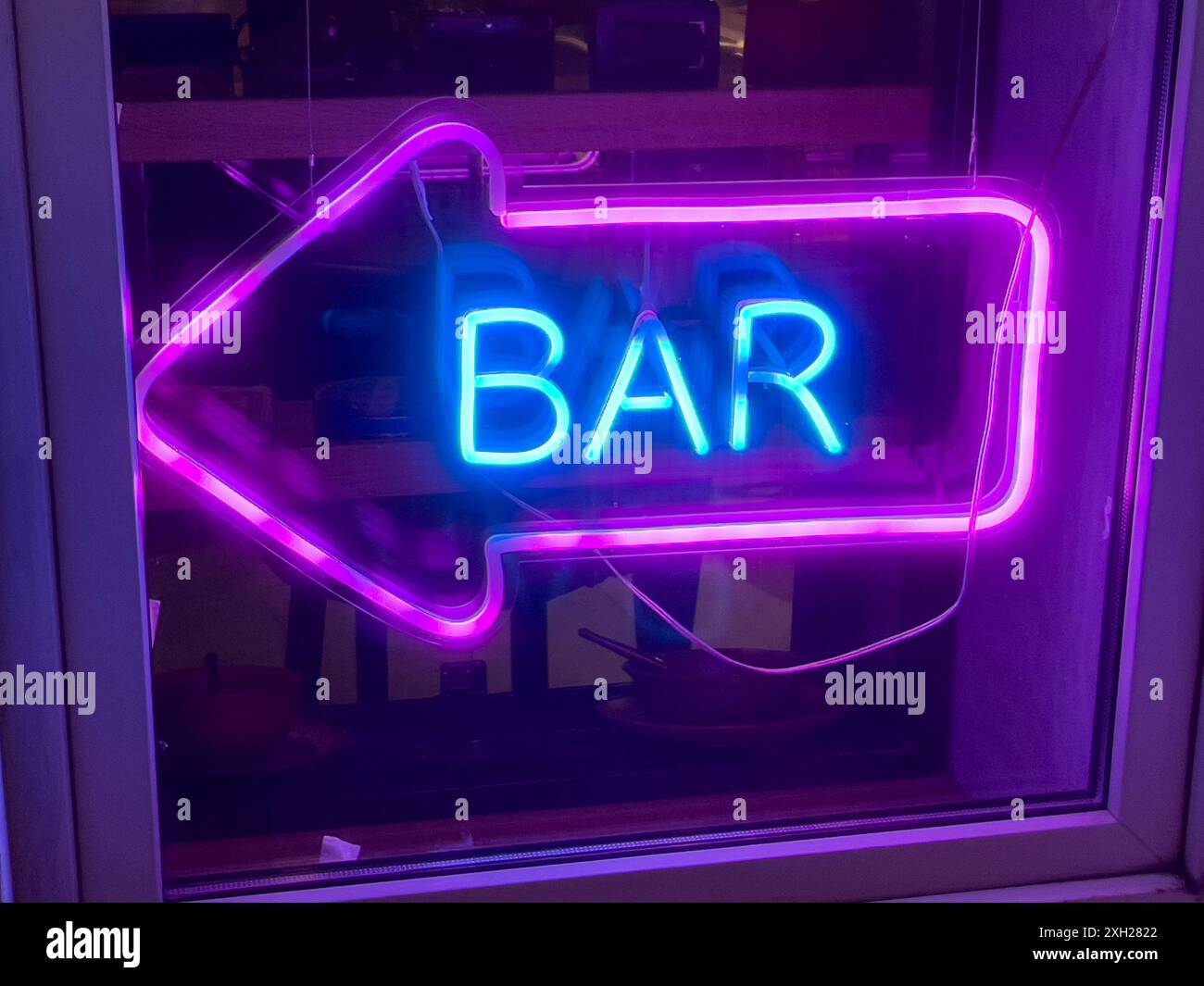 Bright neon bar sign with an arrow pointing left, glowing in vivid ...