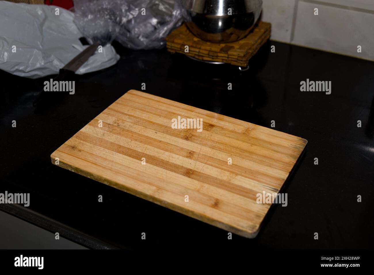 Well-worn wooden chopping board on a clean black countertop, ready for ...