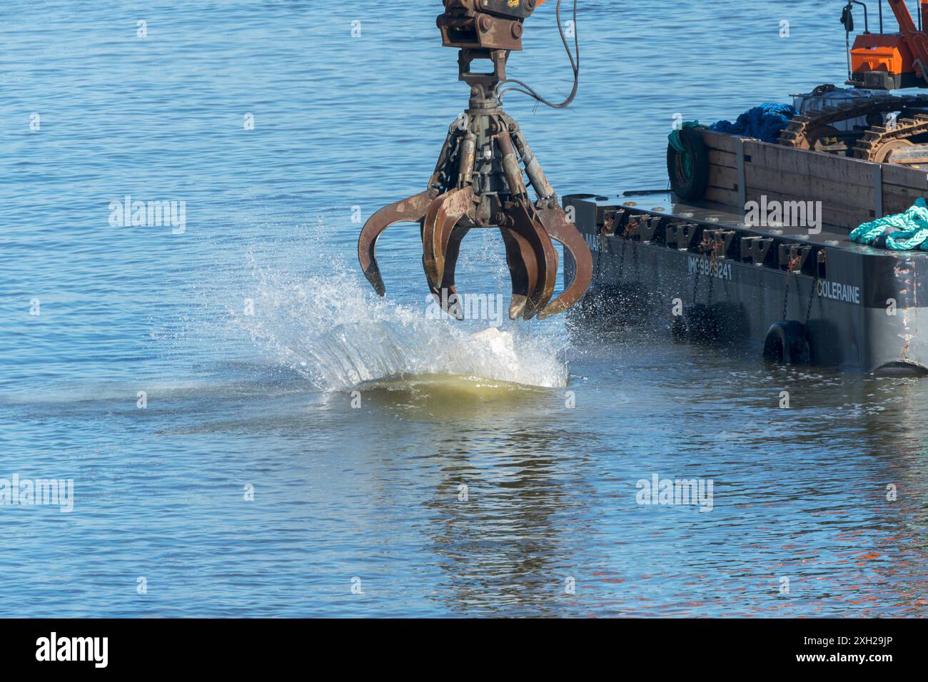 coastal erosion protection work with machinery from a barge at sea ...