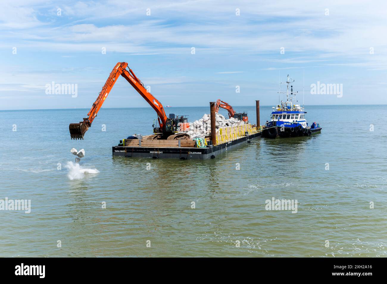 coastal erosion protection work with machinery from a barge at sea ...