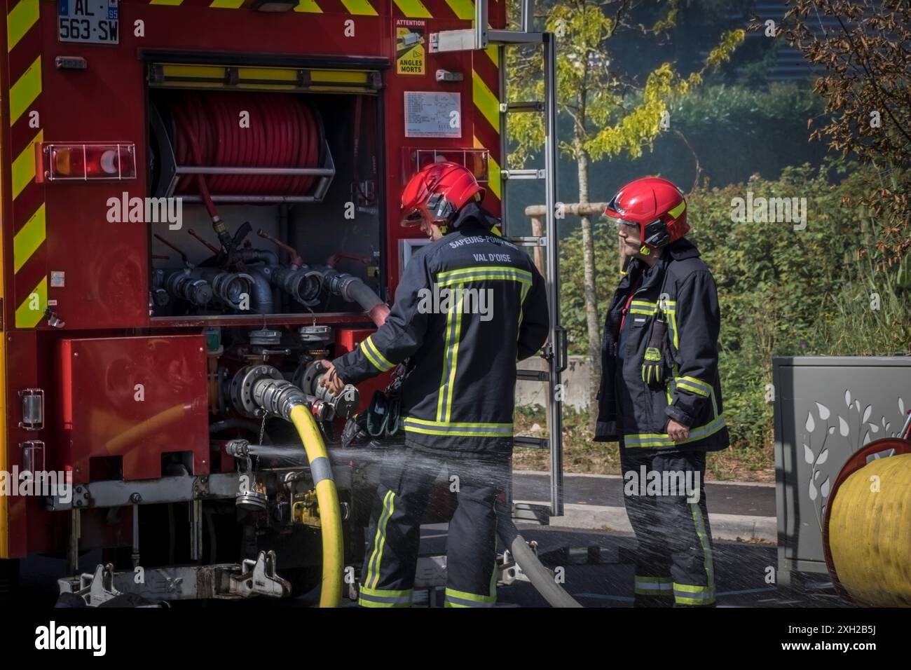 Val D'Oise France. Firefighters damping down potential dry grass ...