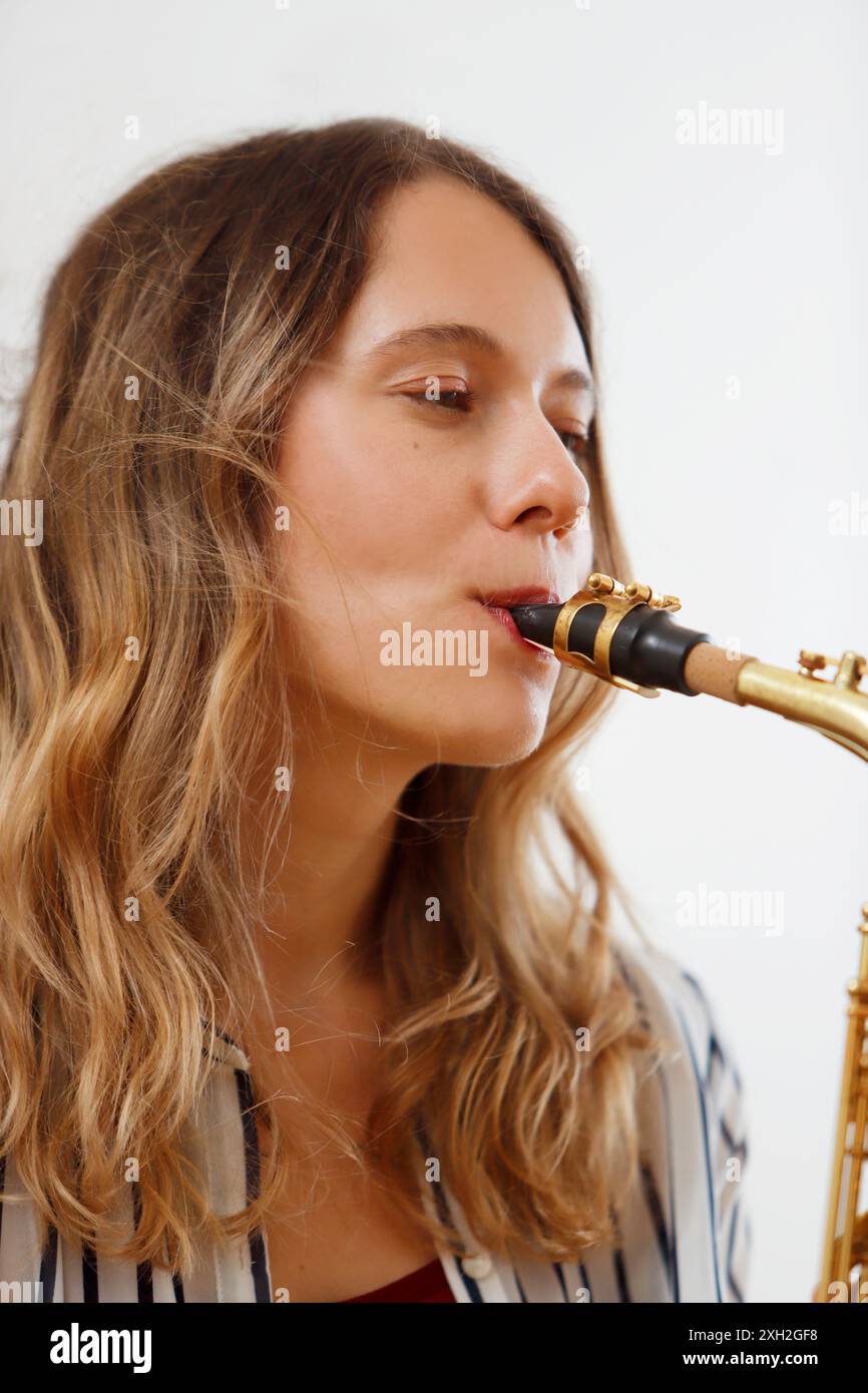 blonde girl playing saxophone on white background Stock Photo - Alamy