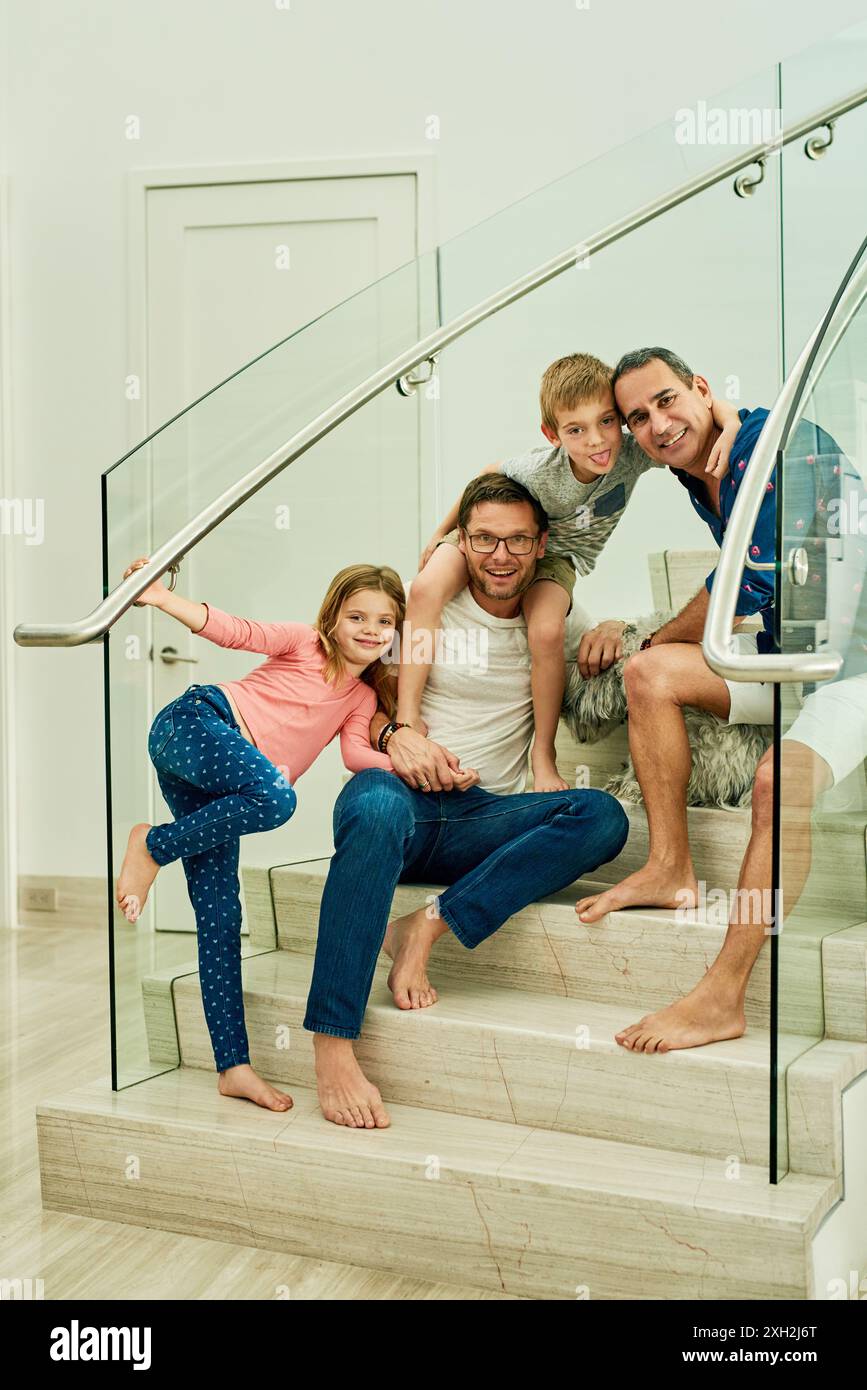 Gay couple, portrait and children with father on home staircase for ...