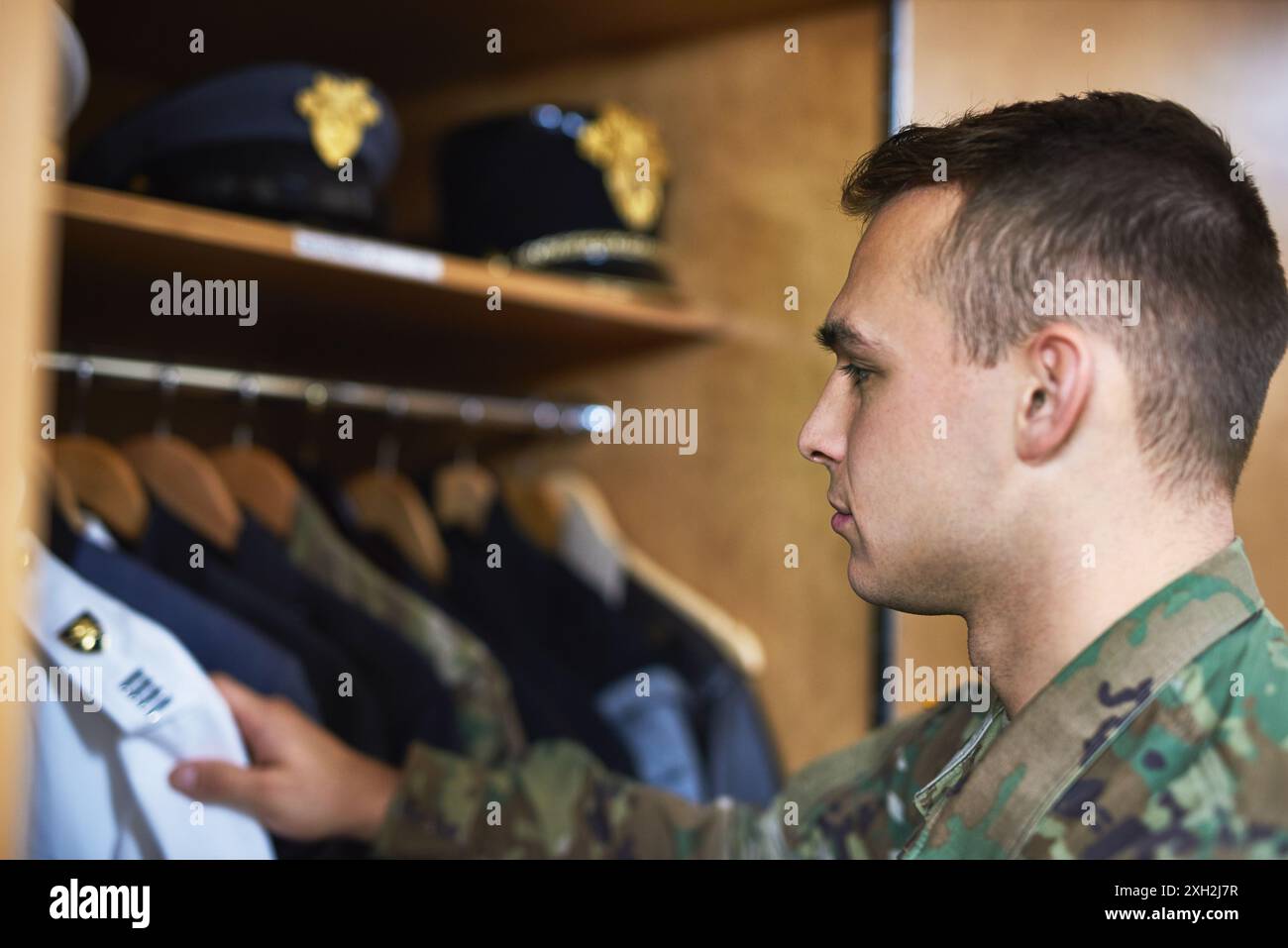 Man, soldier and choice for clothes in closet with badge, gear and ...