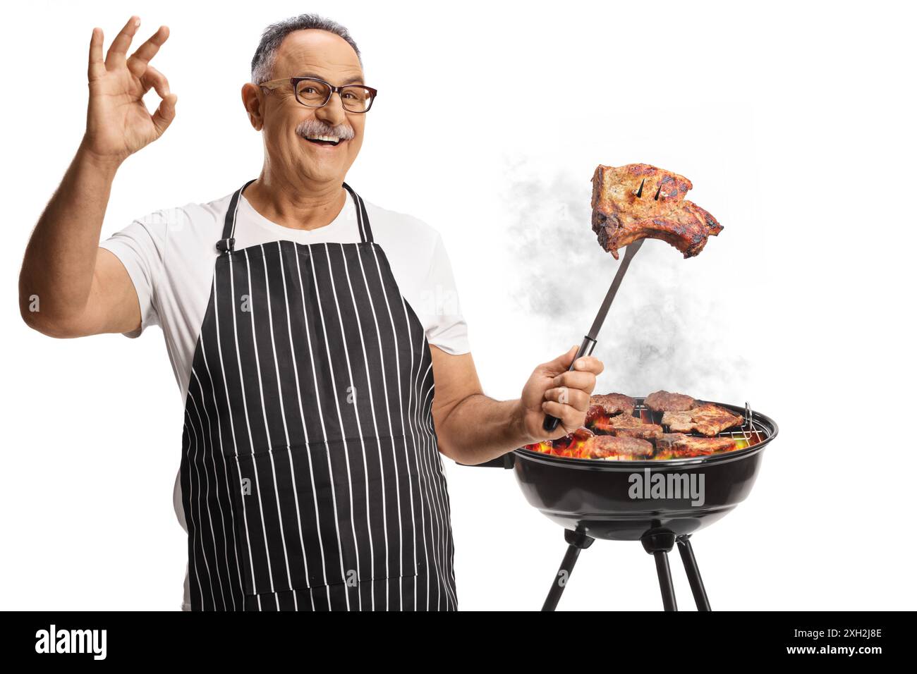 Man grilling meat on a barbecue and holding a steak on a fork isolated ...