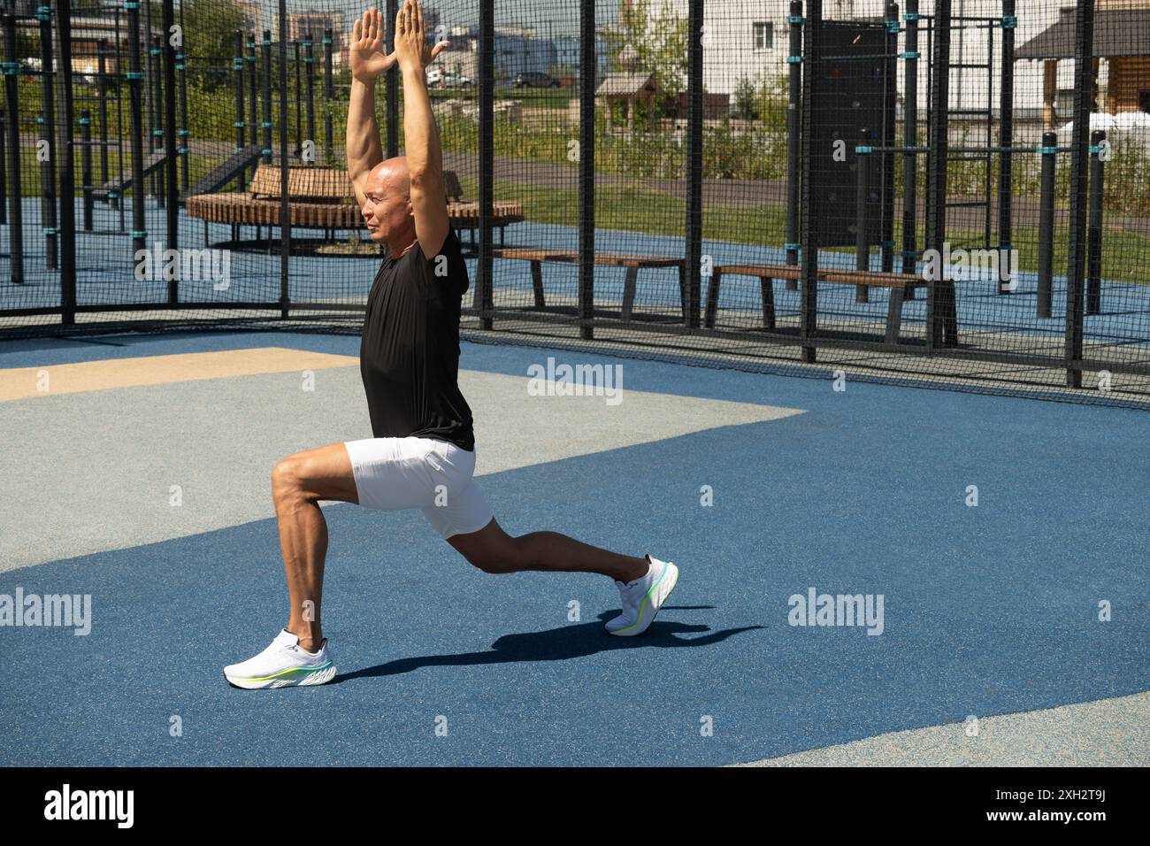 Athlete handsome male make fitness exercises and stretch on courtyard ...
