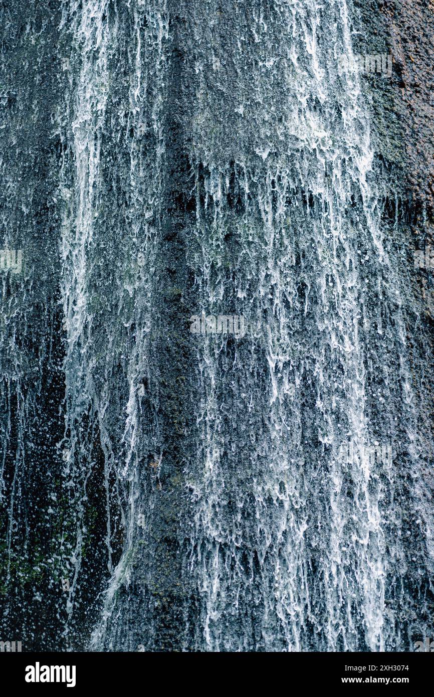 Detailed view of water cascading over rugged rock surface, capturing ...