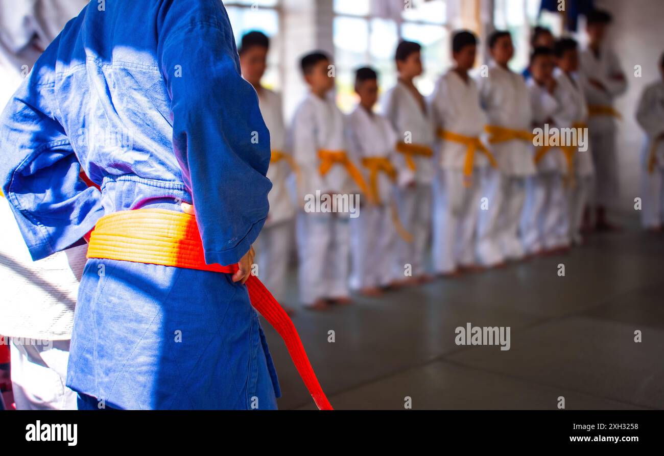 The Children in martial arts class wearing white uniforms with yellow ...