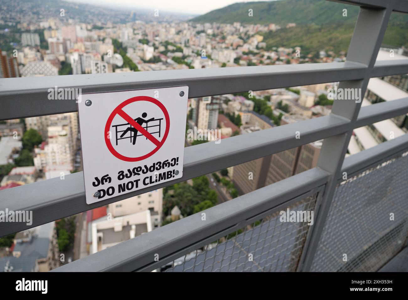 A red warning sign on a rooftop saying DO NOT CLIMB in English and ...