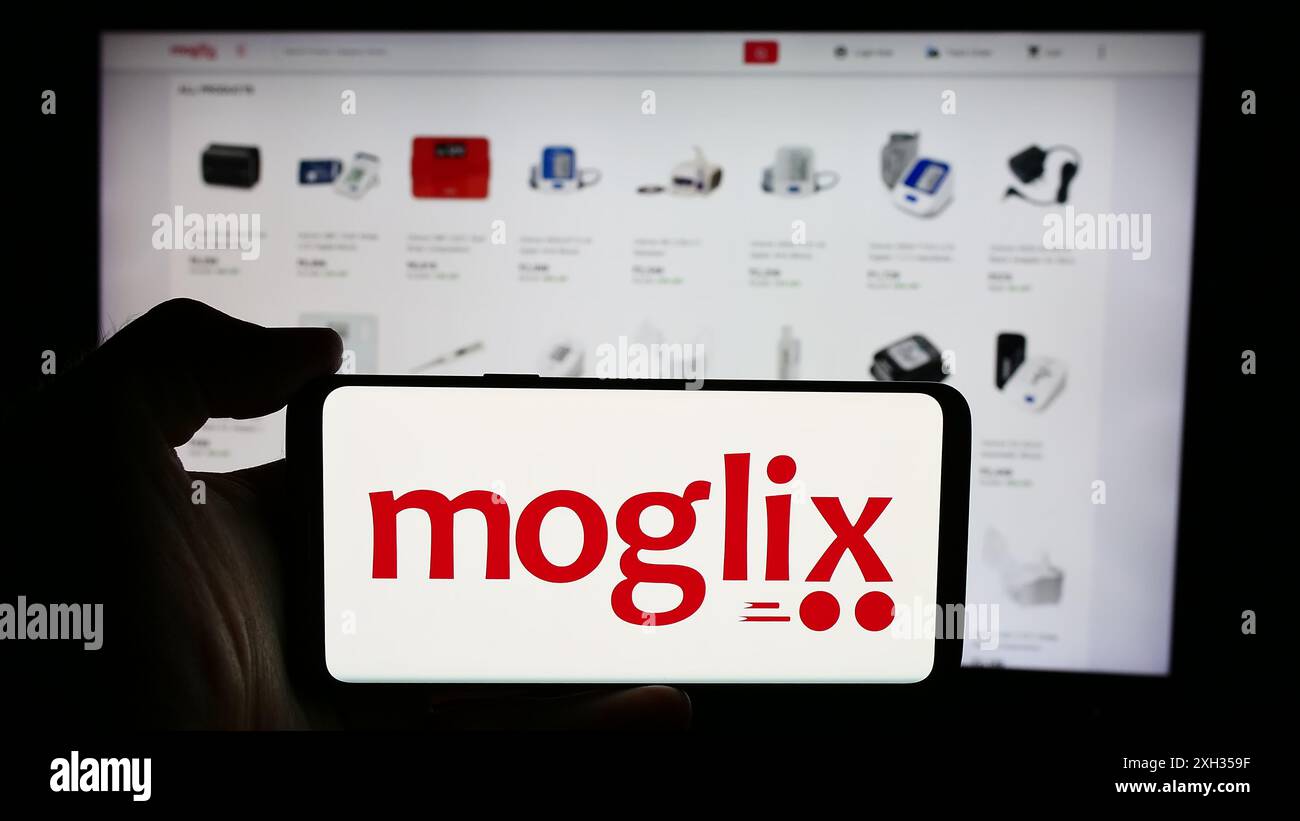 Person holding cellphone with logo of e-commerce company Mogli Labs ...