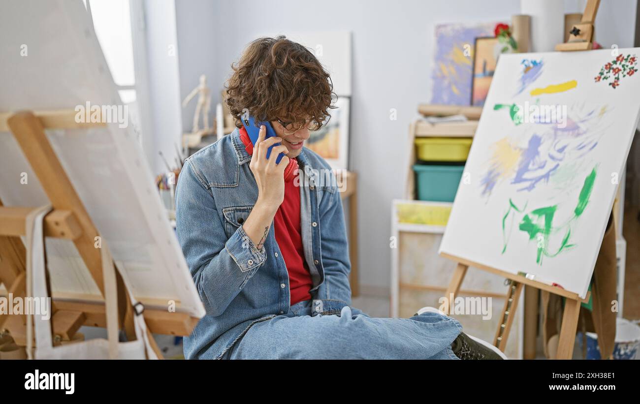 A young artist man talking on the phone in a creative studio with ...