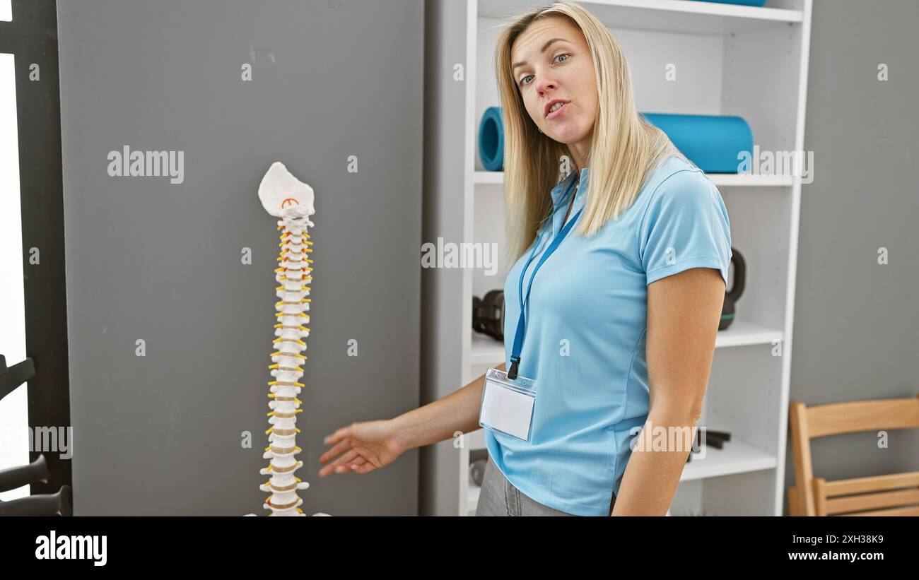 Blonde woman healthcare professional presenting spine model in clinic ...