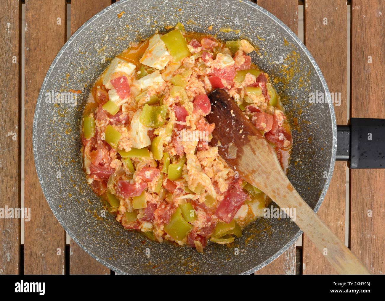 Pan-fried peppers and tomato salsa with Greek cheese in frying pan on ...