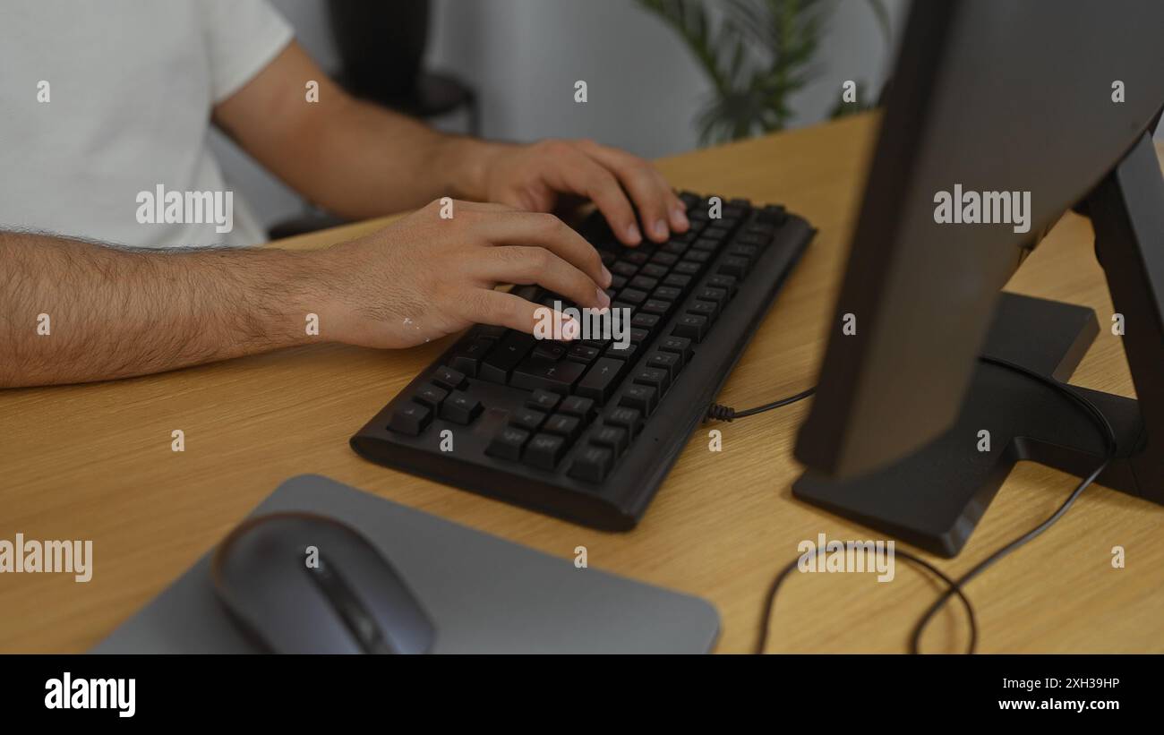 A man typing on a keyboard in an office setting, focusing on his hands ...